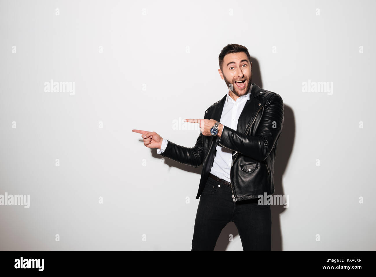 Portrait of a cheerful happy man standing and pointing fingers away ...