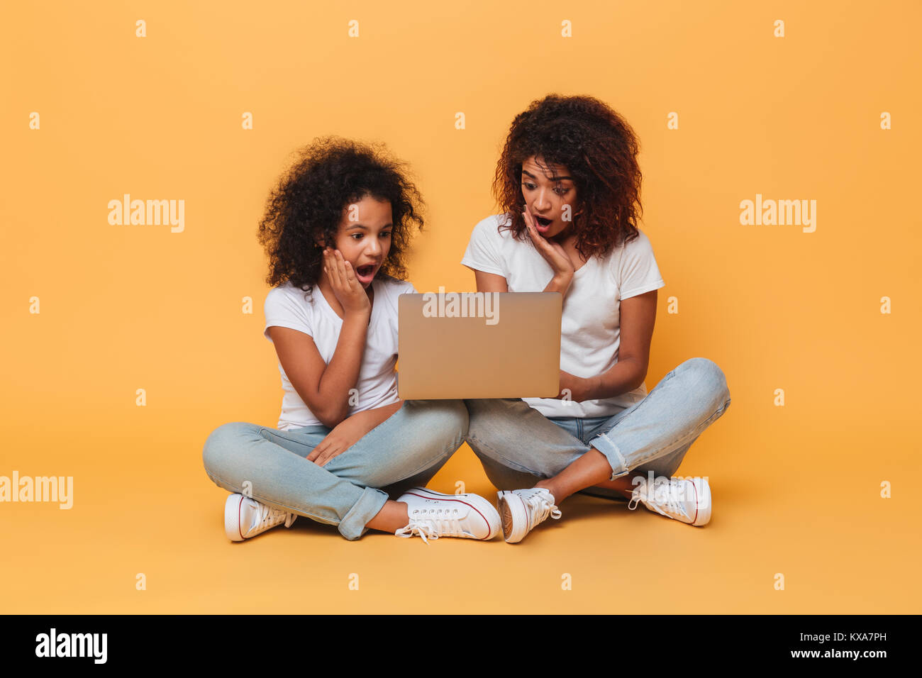 Two surprised afro american sisters using laptop computer while sitting ...