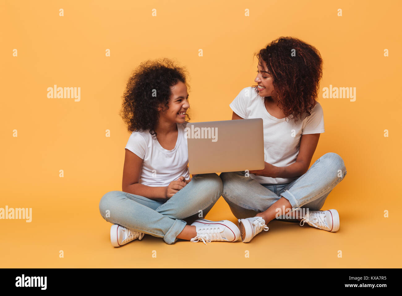 Two joyful afro american sisters using laptop computer while sitting ...