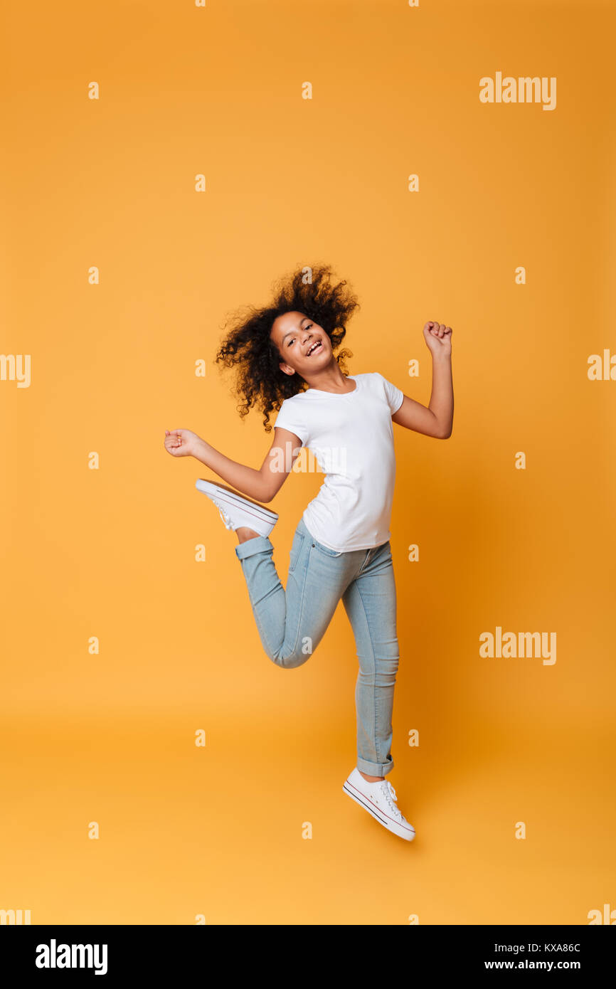 Full length portrait of a cheerful little african girl jumping and ...
