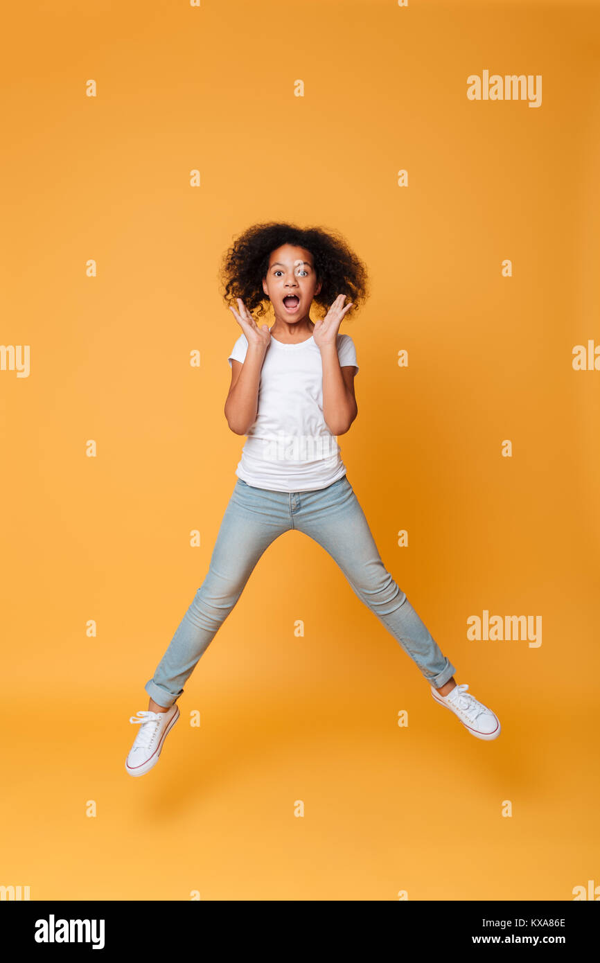 Full length portrait of an excited little african girl jumping and ...