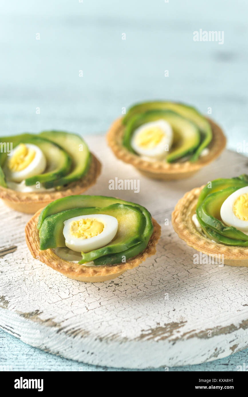 Tartlets with cream cheese, avocado and quail eggs Stock Photo - Alamy