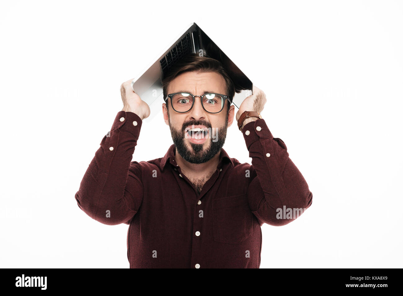 Portrait of a young scared man in eyeglasses holding laptop computer on ...