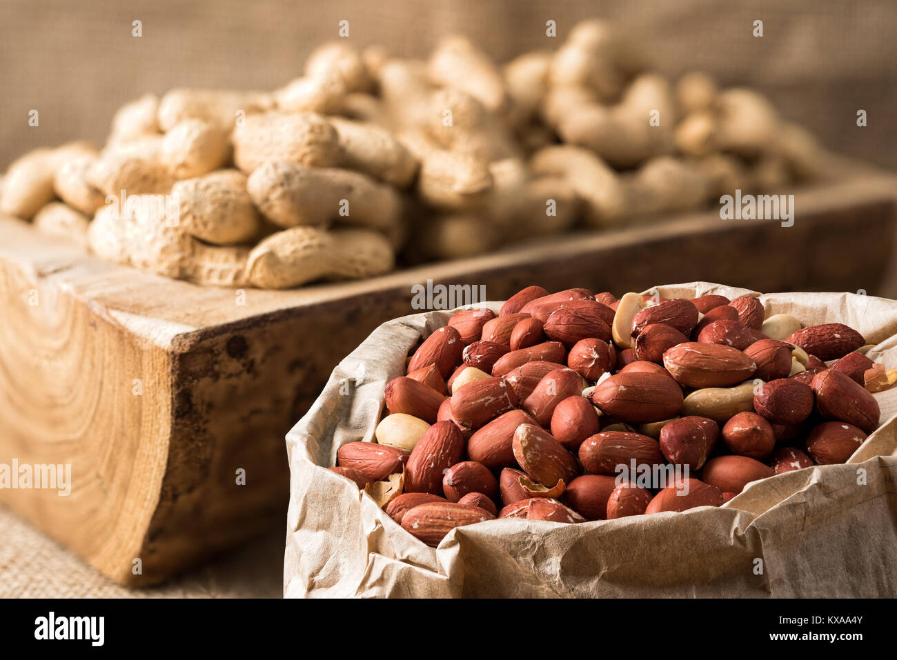 Paper bag full of peeled peanuts and peanuts in nutshell on a piece of ...