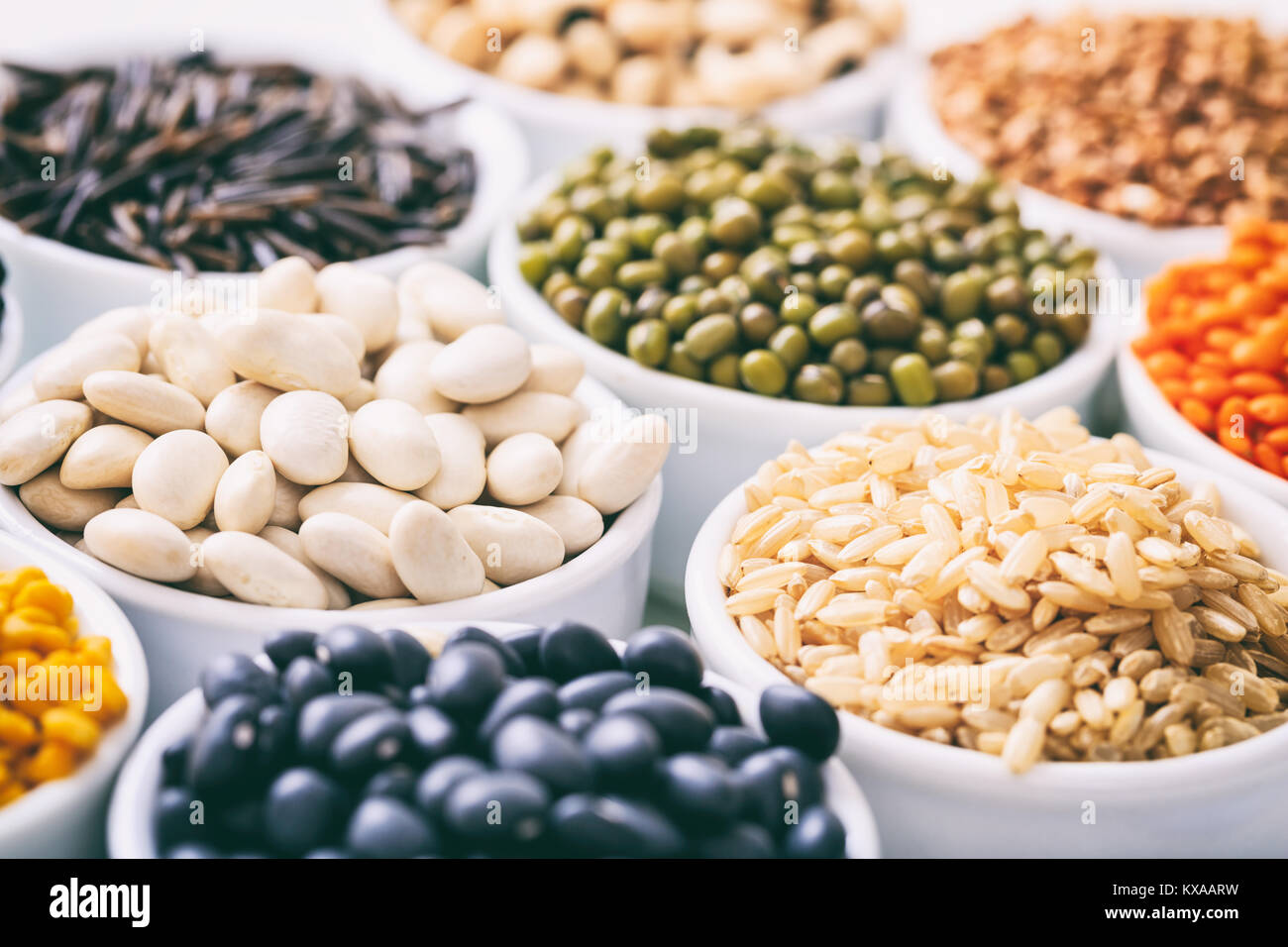 Various raw legumes and rice in white bowls Stock Photo - Alamy