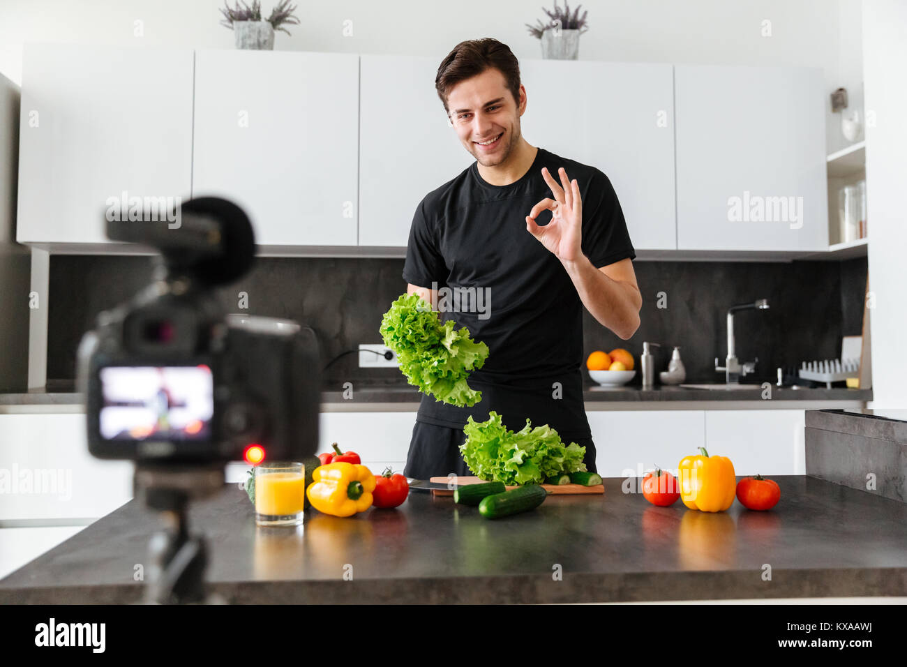 Smiling young man filming his video blog episode about healthy food ...