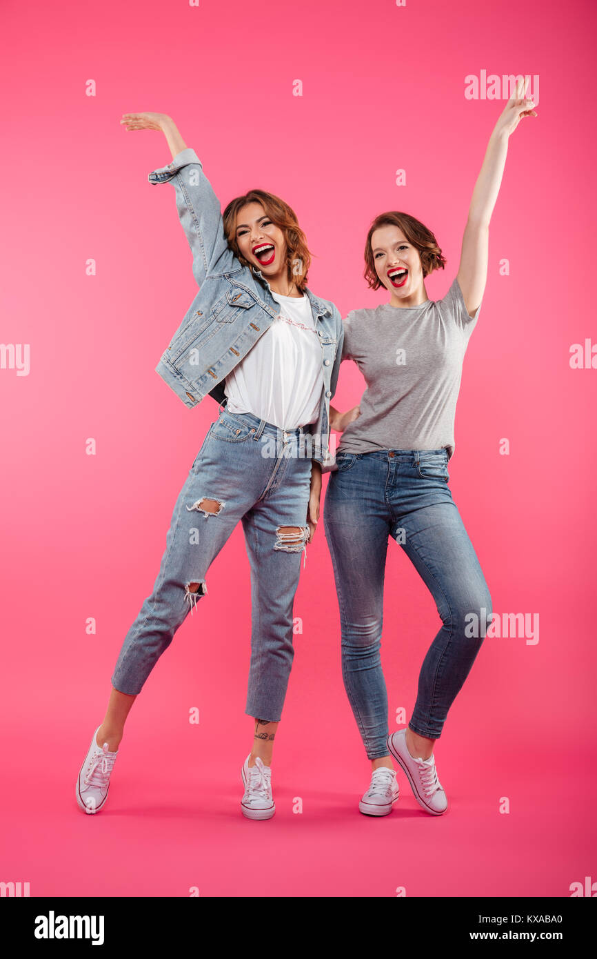 Image of happy two ladies friends standing isolated over pink ...