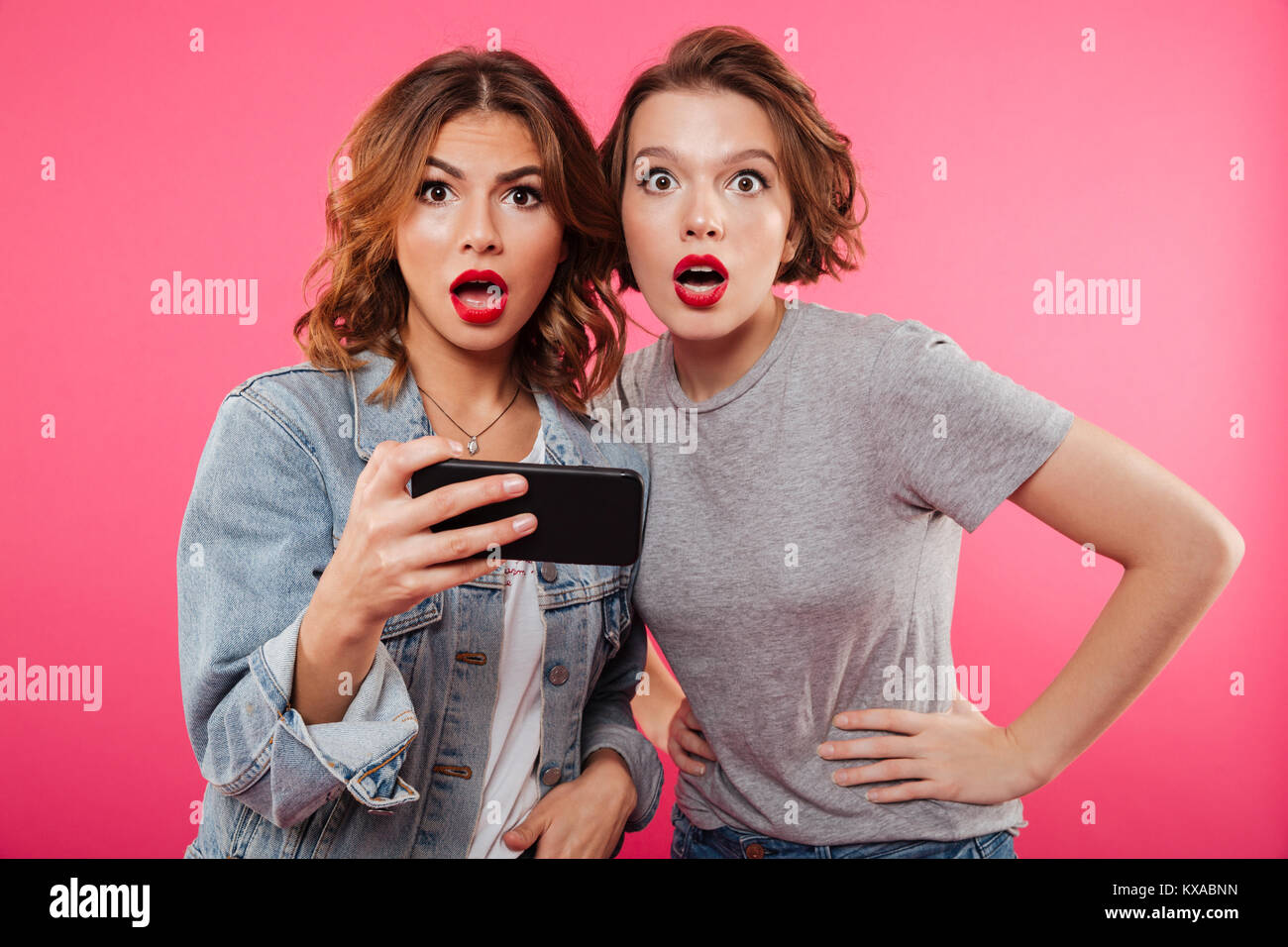 Image of two shocked ladies friends standing isolated over pink ...