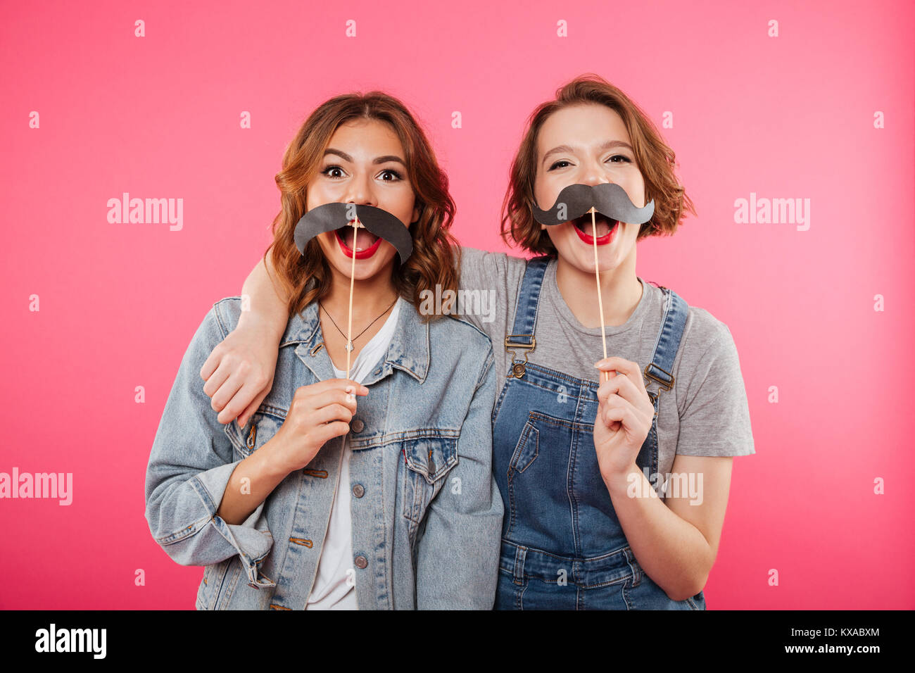 Image of two funny women friends standing isolated over pink background ...