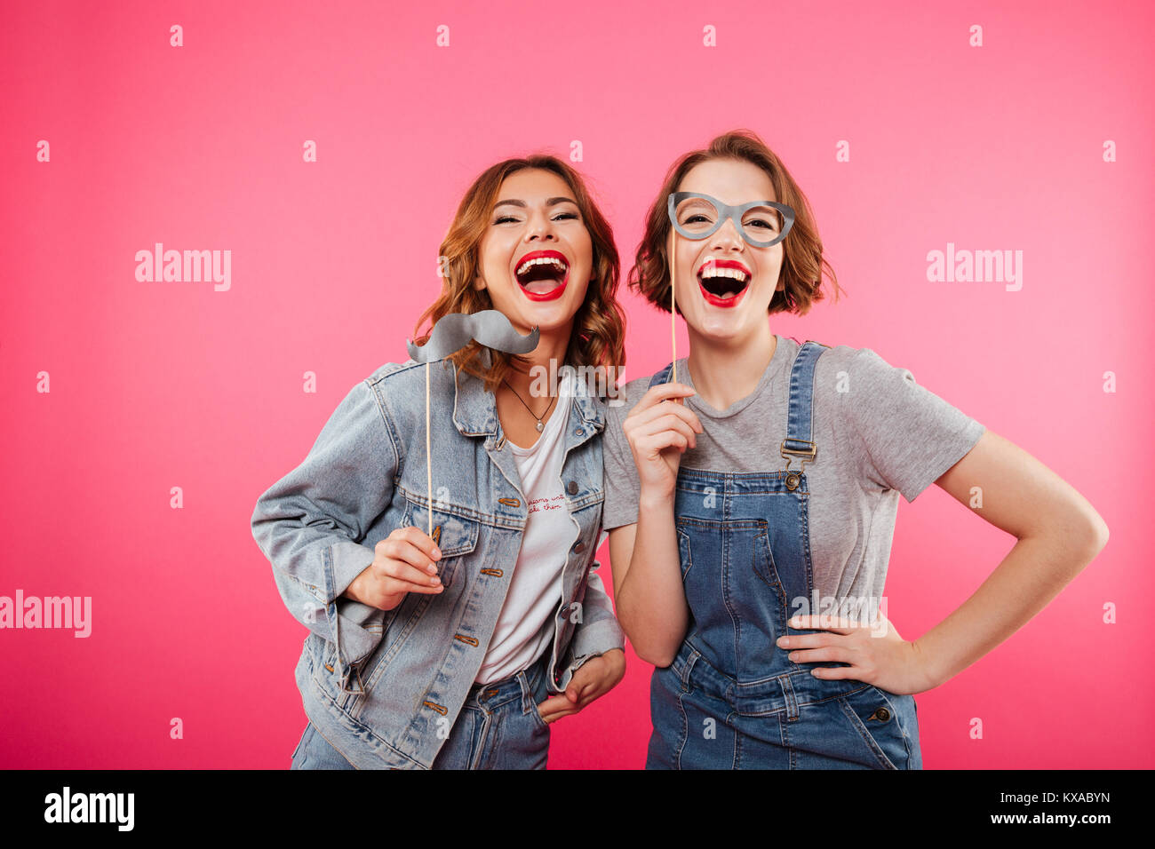 Image of two funny women friends standing isolated over pink background ...
