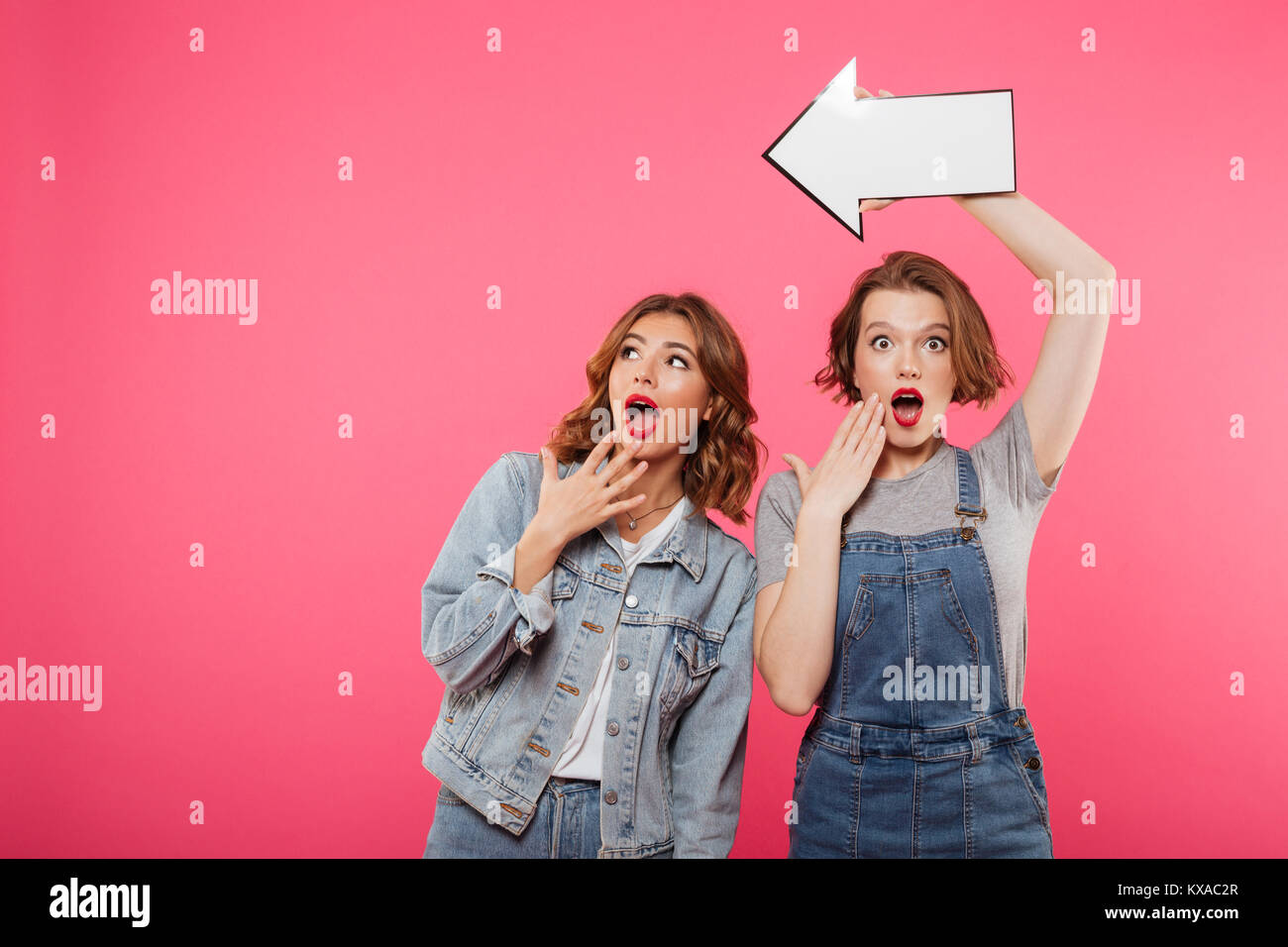 Photo of shocked two ladies friends standing isolated over pink ...