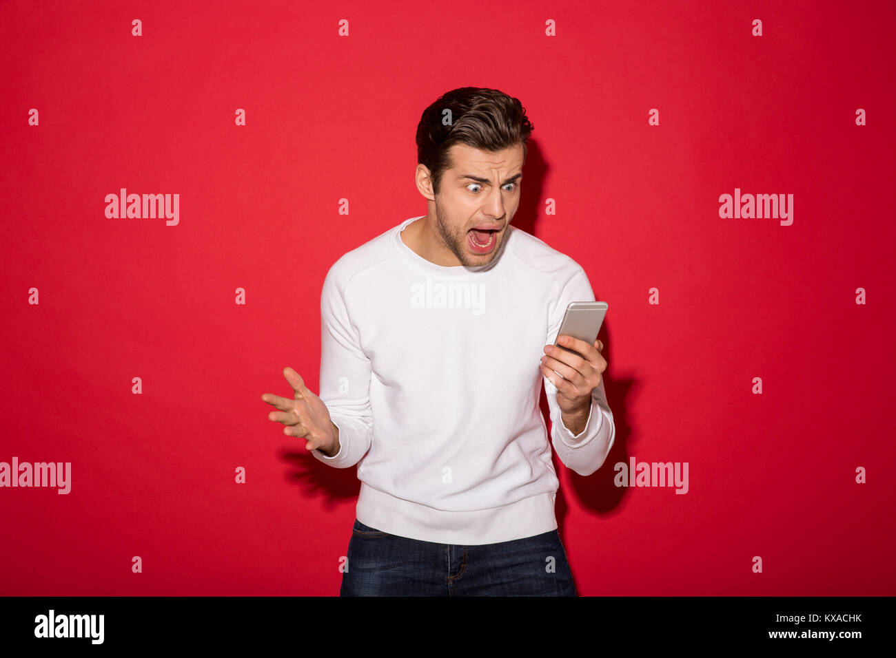 Picture of angry man in sweater screaming at smartphone over red ...