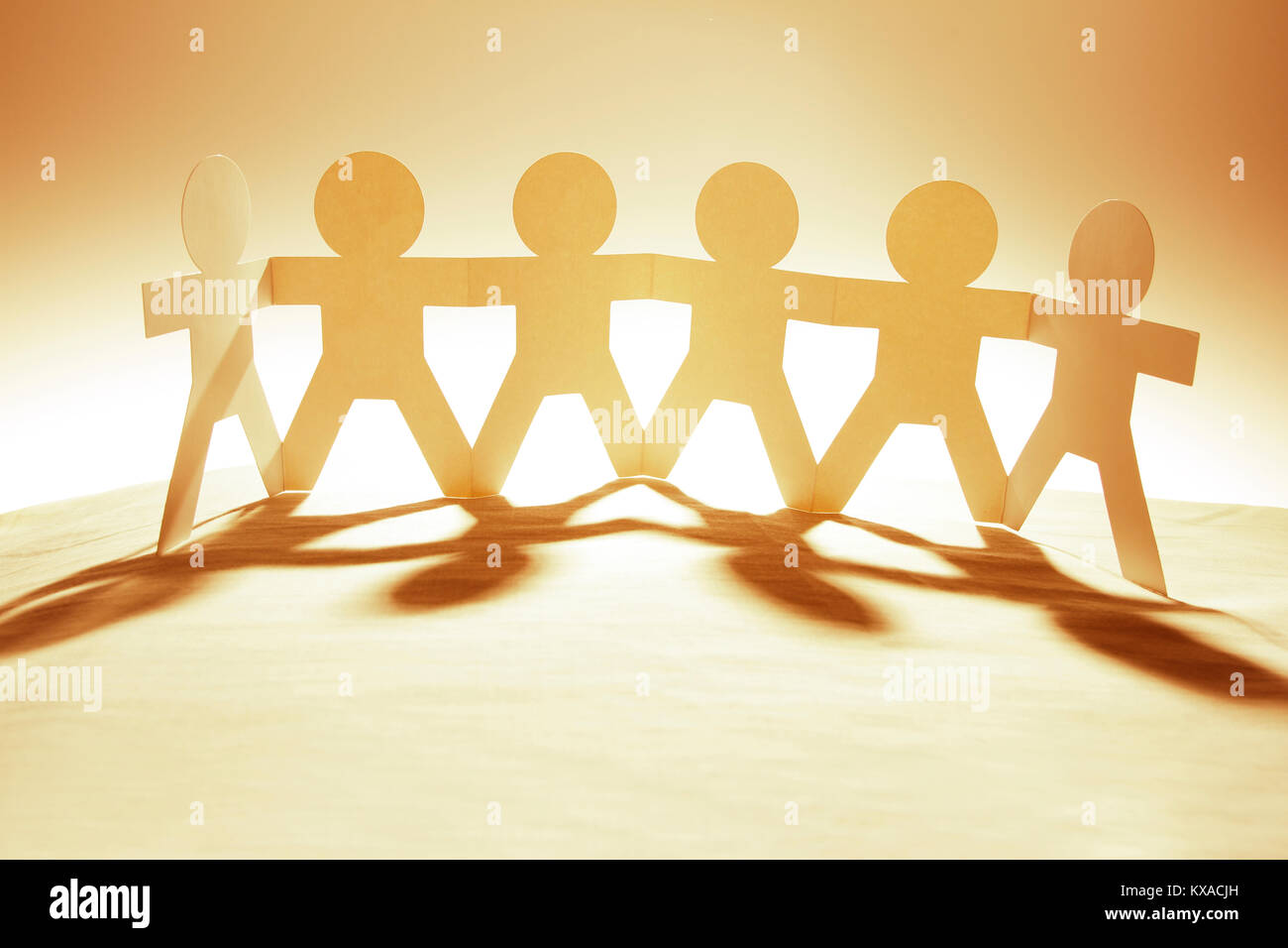 Team of paper chain people in a row holding hands Stock Photo - Alamy