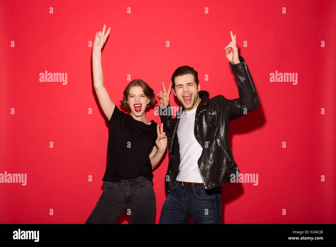 Happy punk couple showing peace gestures and looking at the camera over ...