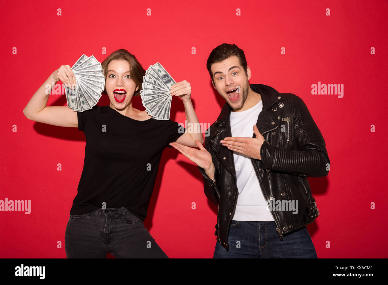 Happy punk woman showing the money while punk man posing near her and ...