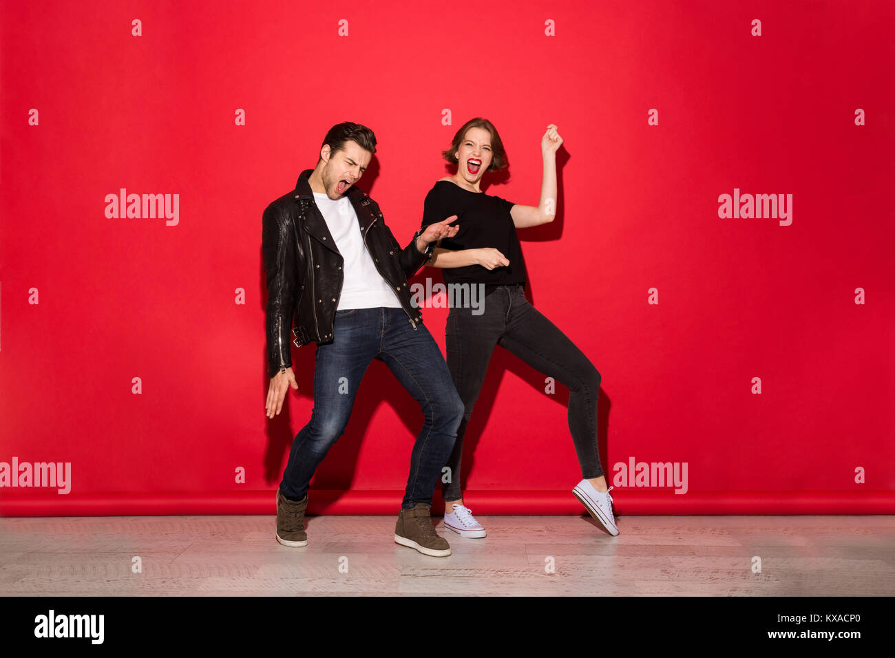 Full length image of playful punk couple dancing in studio over red ...
