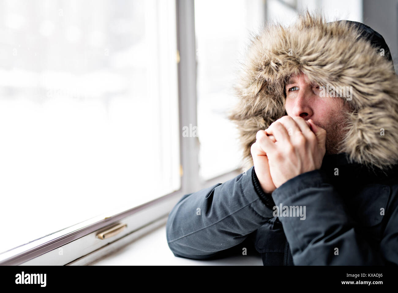 Man With Warm Clothing Feeling The Cold Inside House close to a window ...