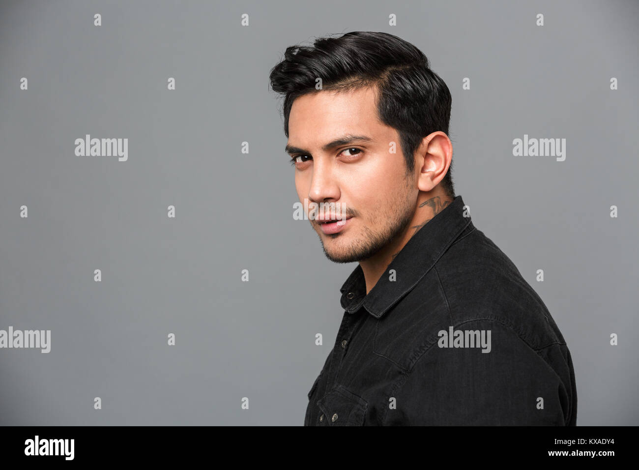Picture of handsome young serious man standing isolated over grey wall ...