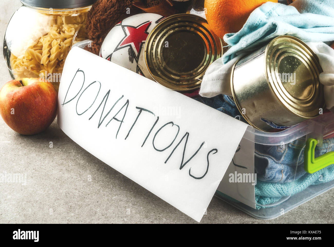 Plastic donation box with toys, clothes and food, white grey background ...