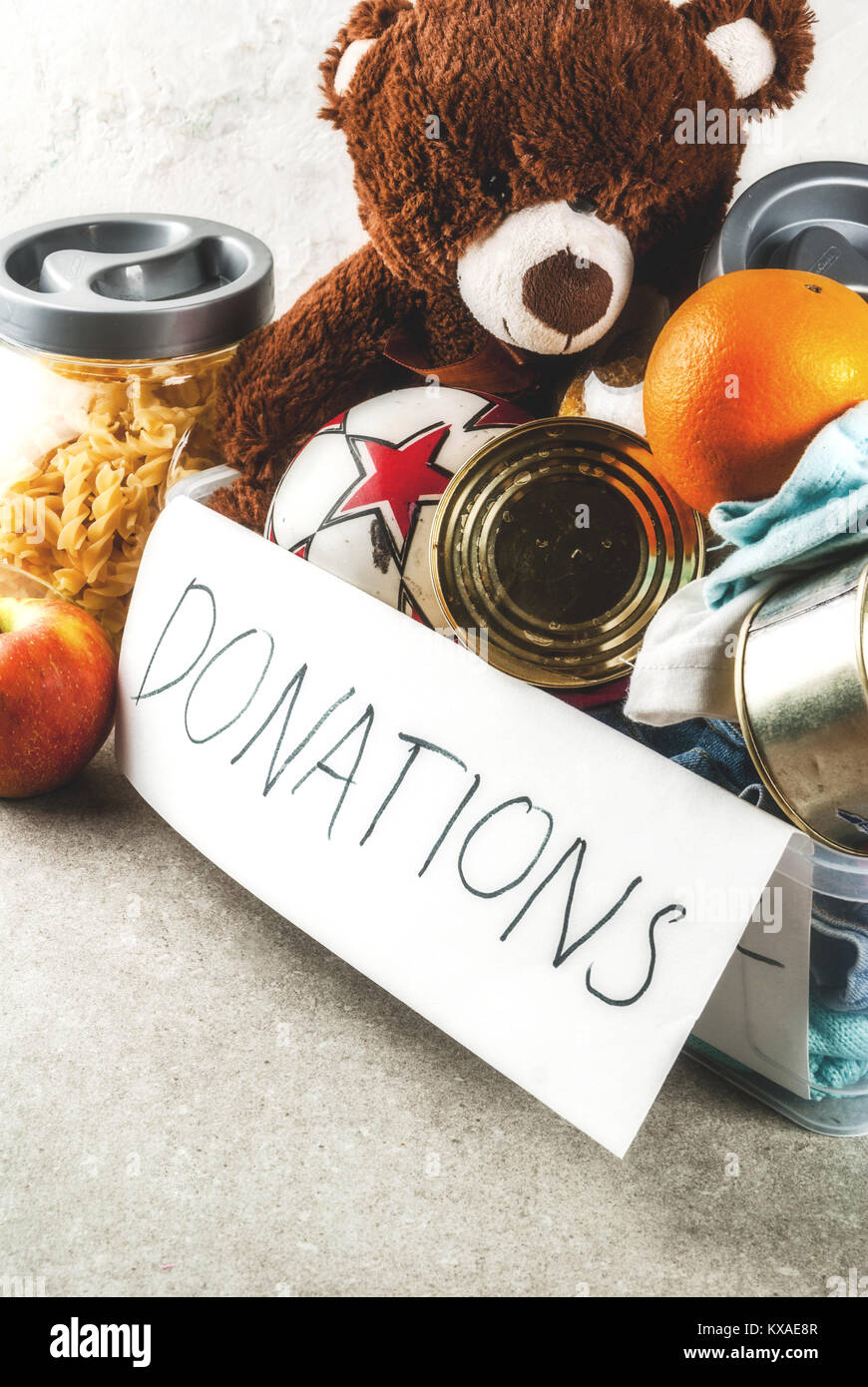 Plastic donation box with toys, clothes and food, white grey background ...