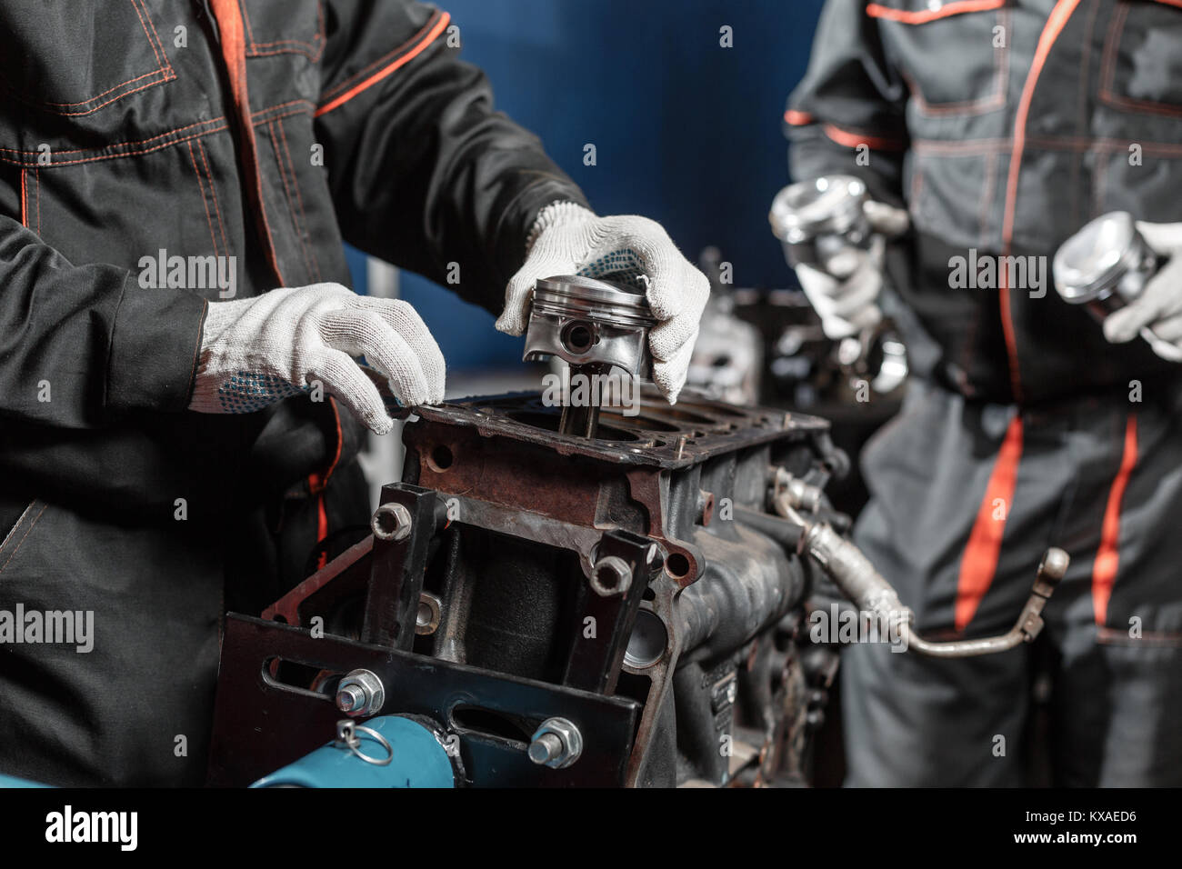 two worker, the mechanic installs a new piston. Disassemble engine ...
