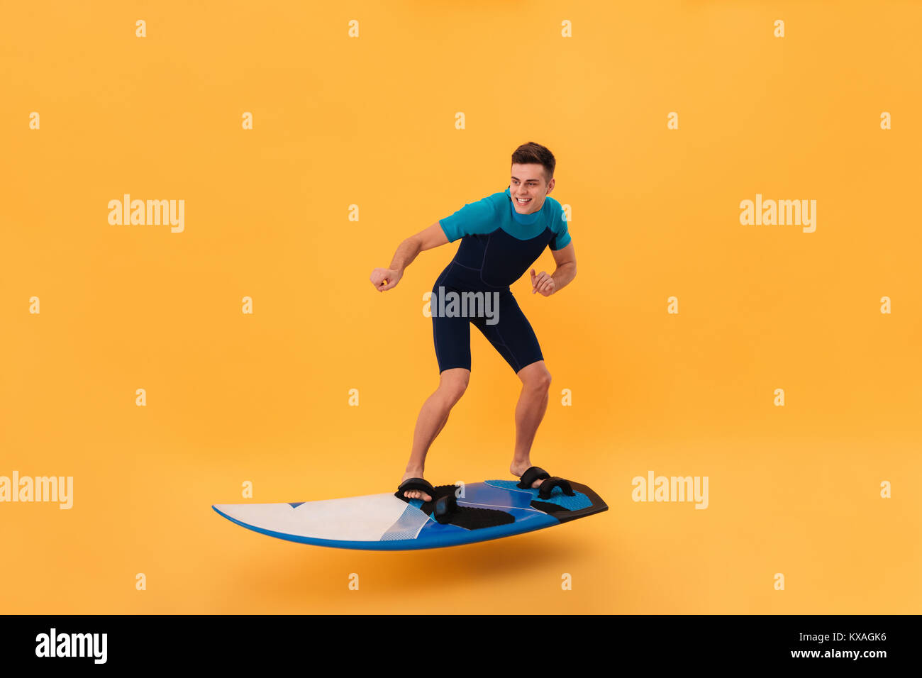 Picture of a Smiling surfer in wetsuit using surfboard like on wave ...