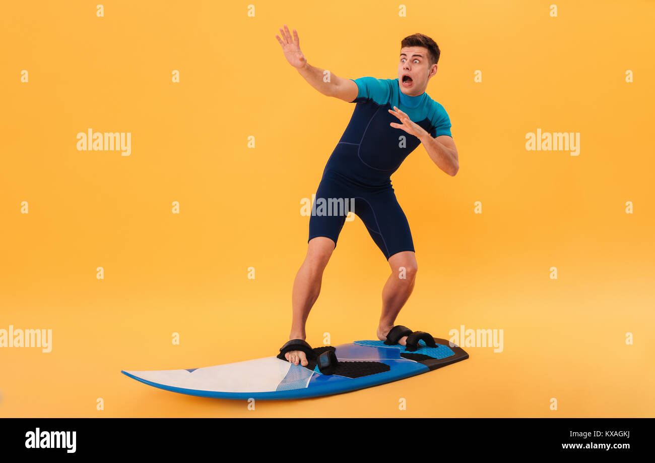 Image of Scared screaming surfer in wetsuit using surfboard like on ...