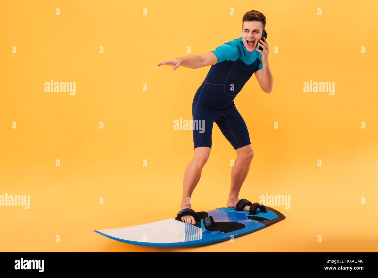 Image of Smiling surfer in wetsuit using surfboard while talking by ...