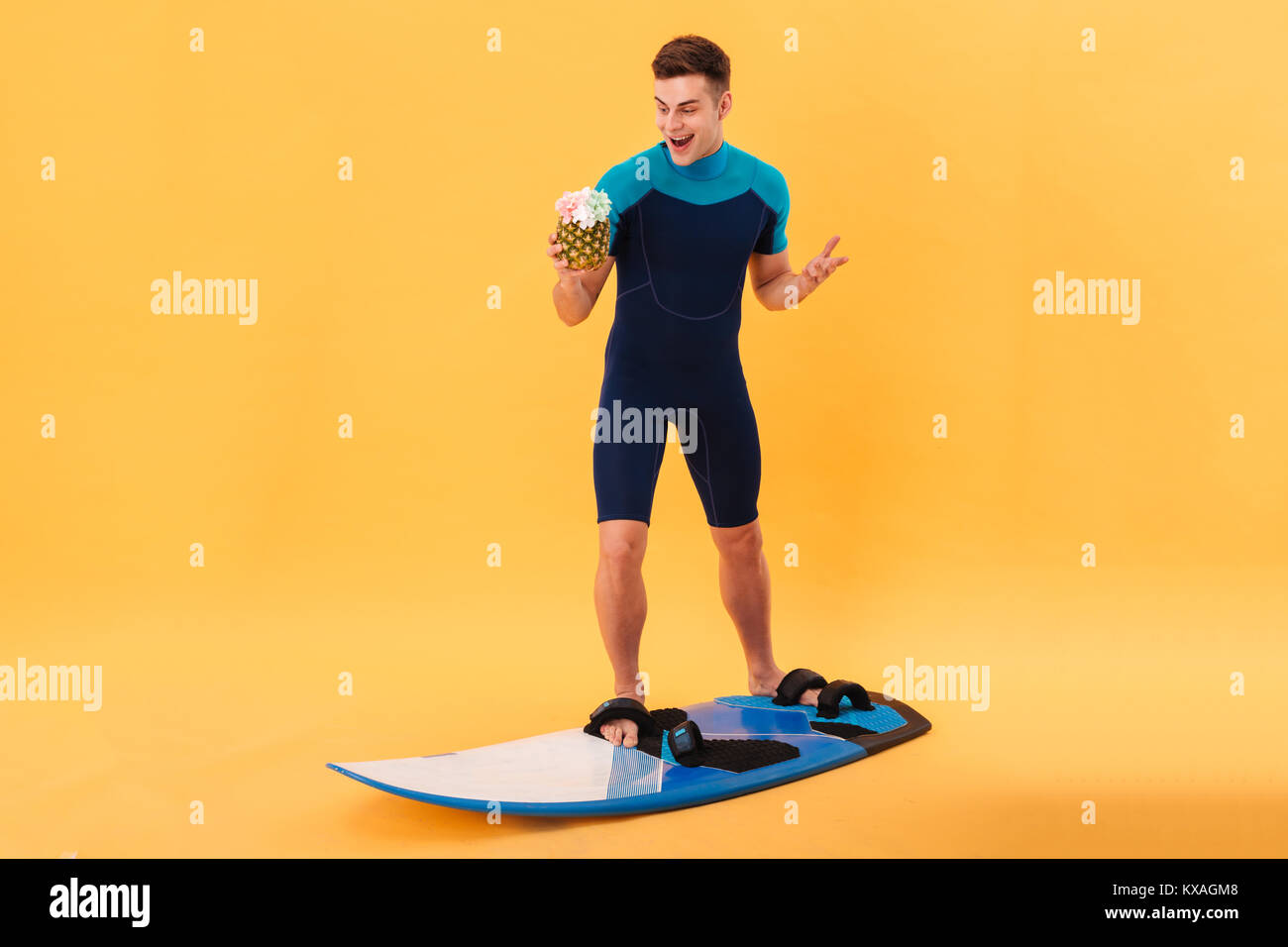 Full length image of Surprised happy surfer in wetsuit using surfboard ...