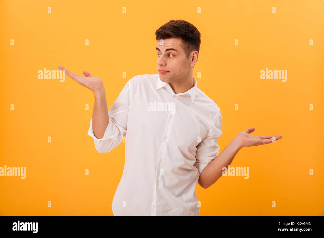 Confused man in white shirt shrugs his shoulder and looking away over ...