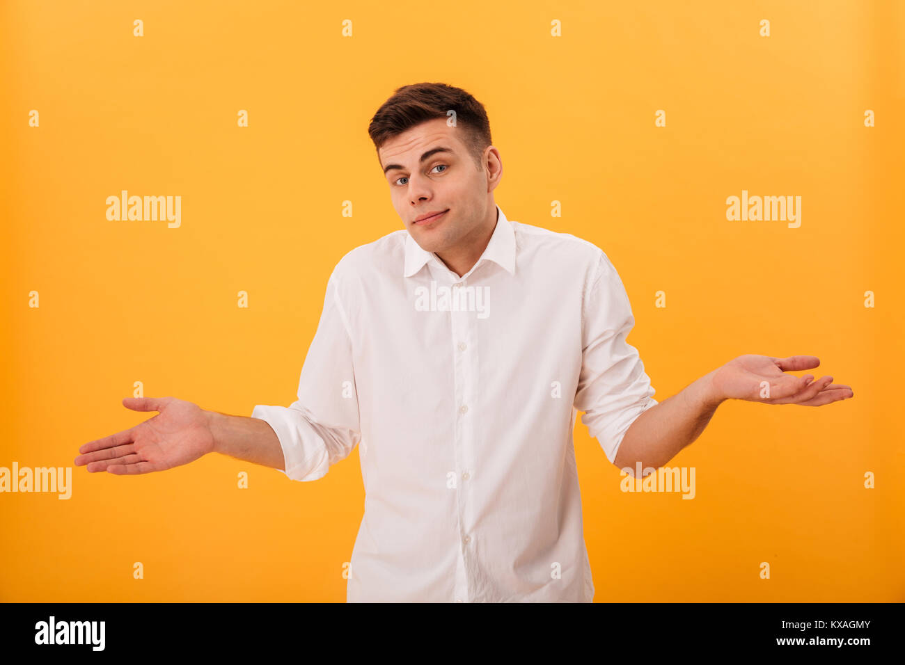 Confused man in white shirt shrugs his shoulder and looking at the ...