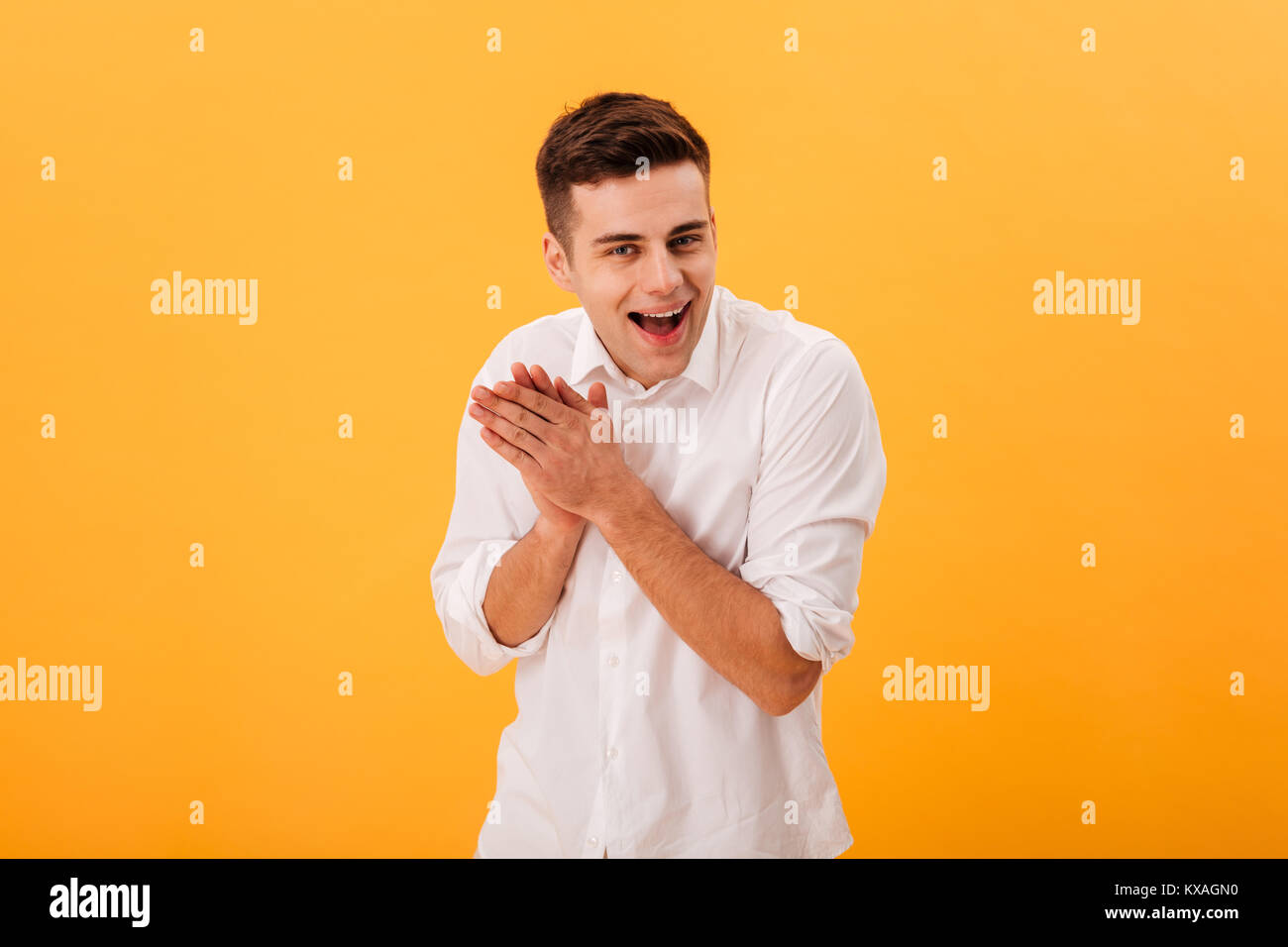 Happy sly man in white shirt holding hands together and looking at the ...