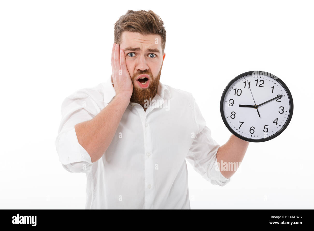 Worried bearded man in business clothes holding clock and looking at ...