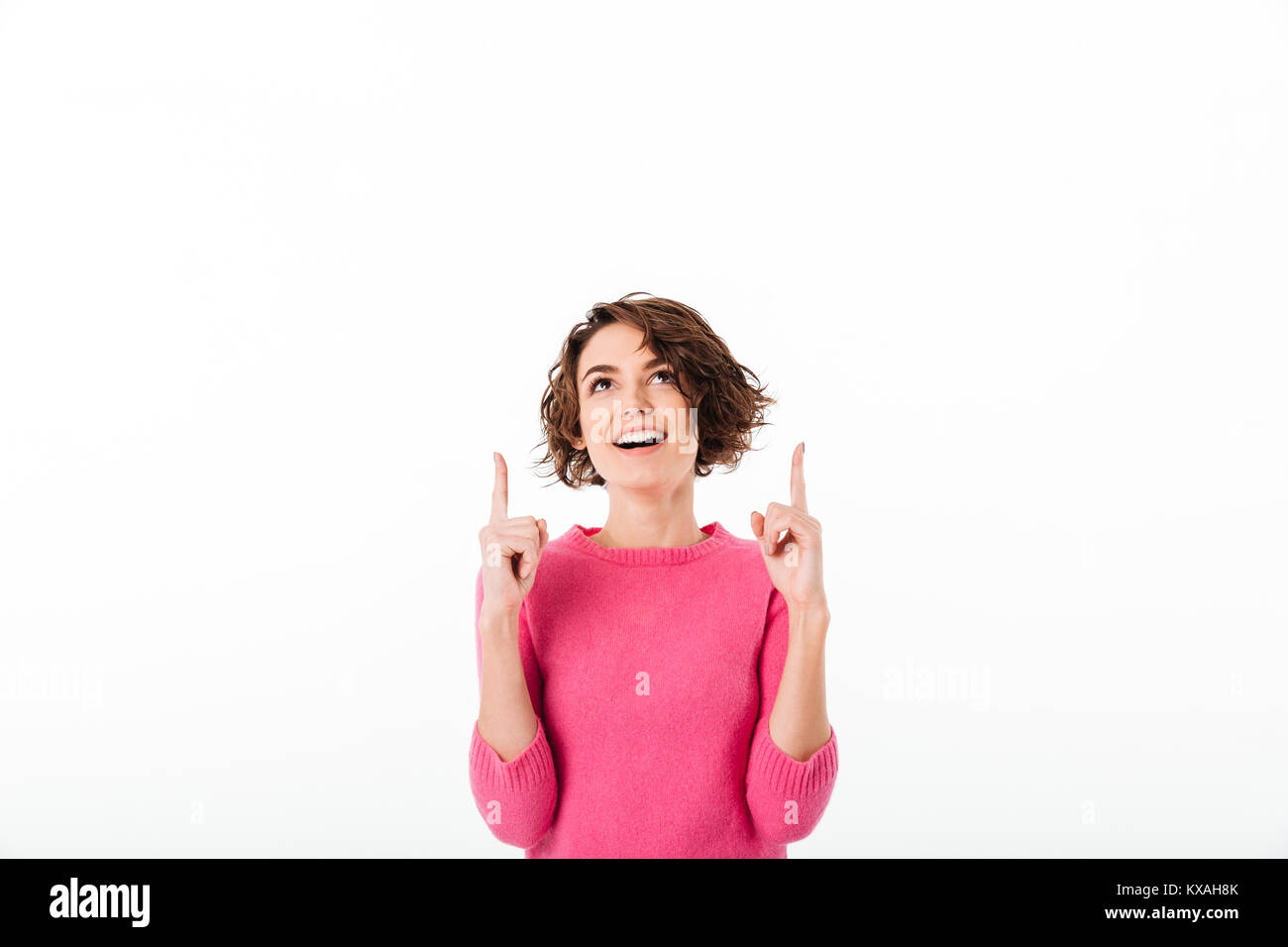 Portrait of a happy pretty girl pointing two fingers up at copy space ...