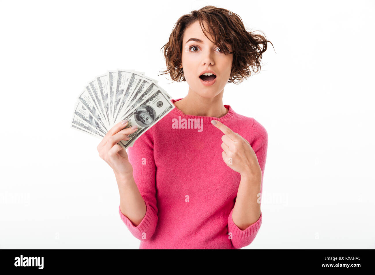 Portrait of an excited pretty girl pointing finger at bunch of money ...