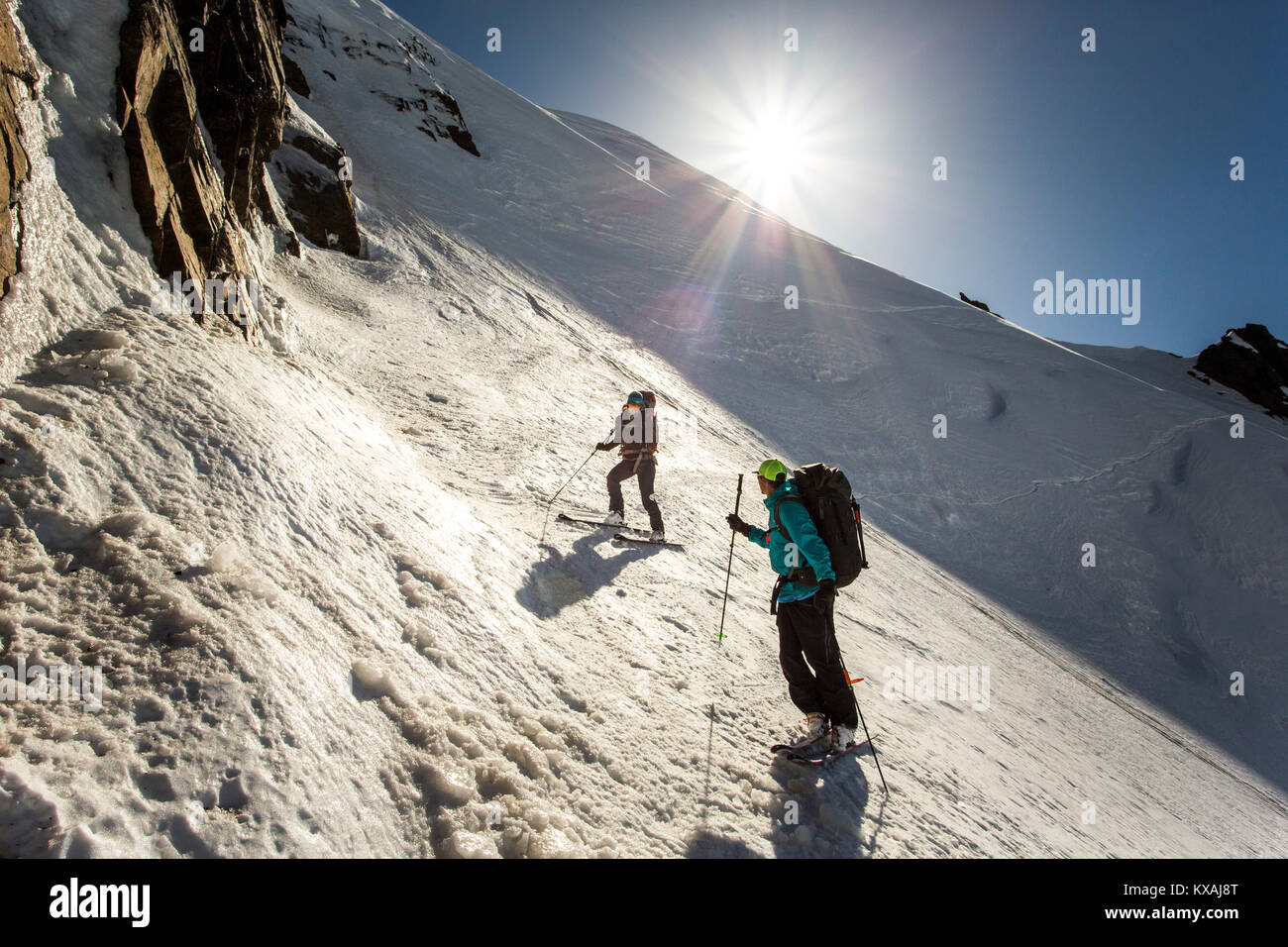 Sun shining over two skiers descending steep slope, Leavenworth ...