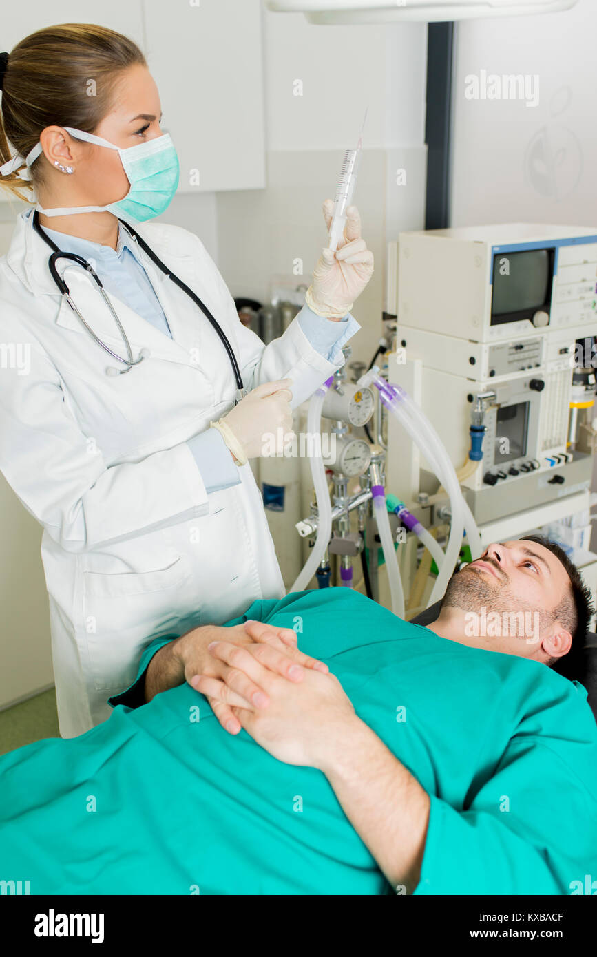 Young female doctor preparing syringe for male patient in the hospital ...