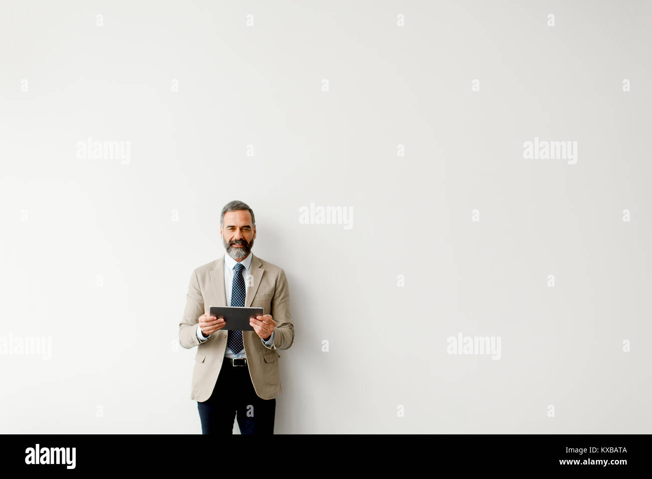 Portrait of handsome senior businessman with tablet by wall Stock Photo ... Portrait of handsome senior businessman with tablet by wall Stock Photo ...