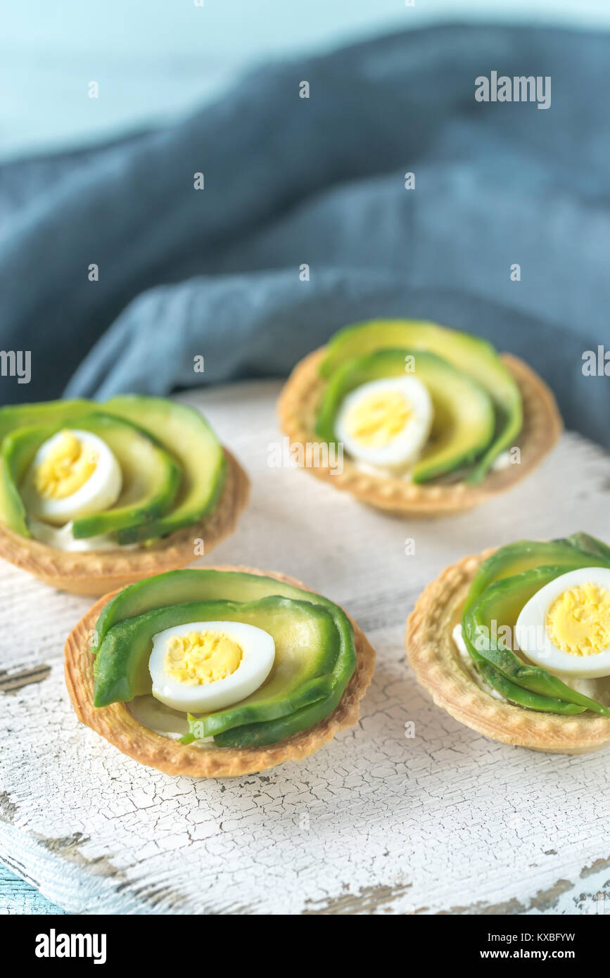 Tartlets with cream cheese, avocado and quail eggs Stock Photo - Alamy