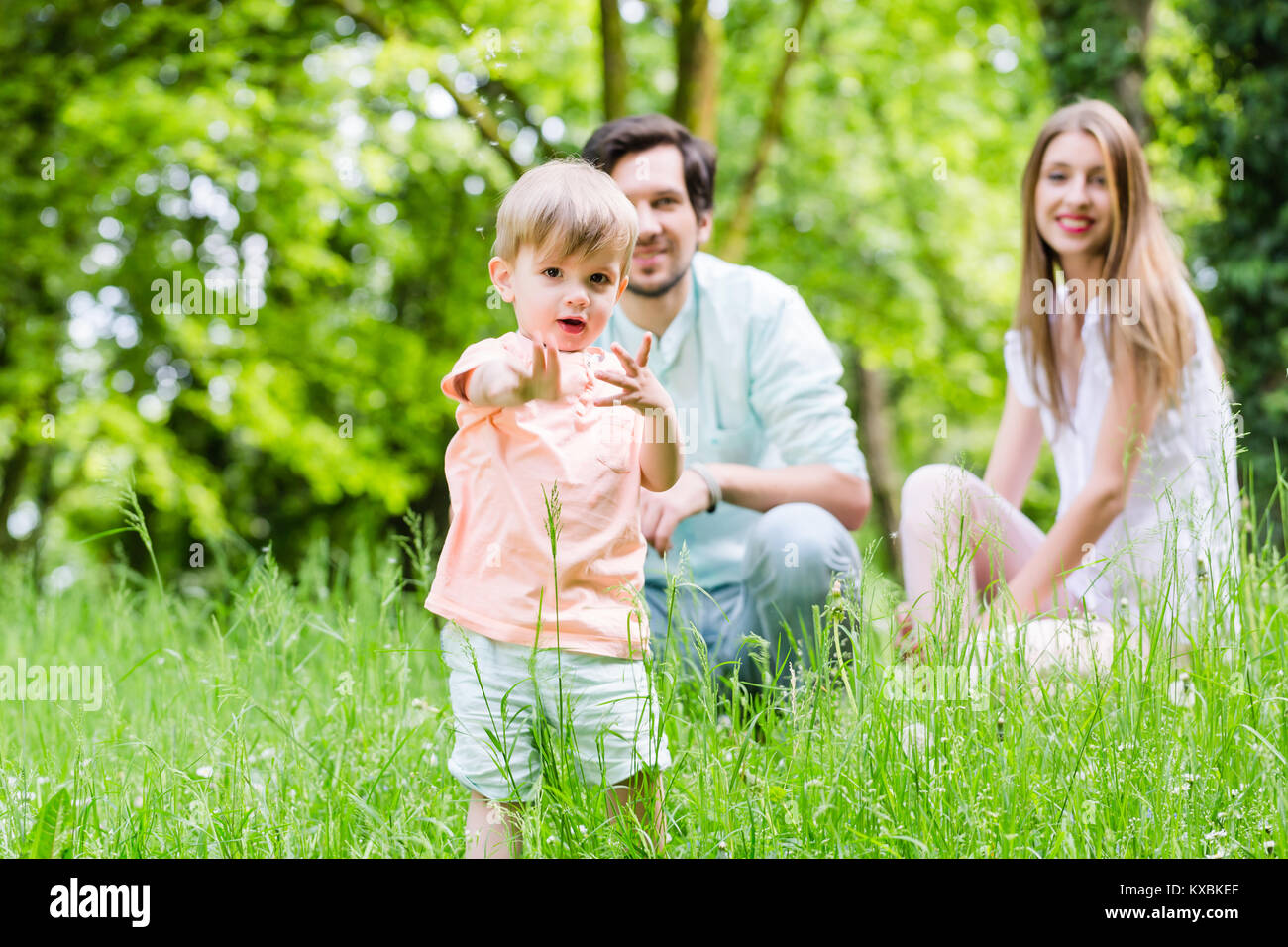 Little boy running over meadow with family in back Stock Photo - Alamy