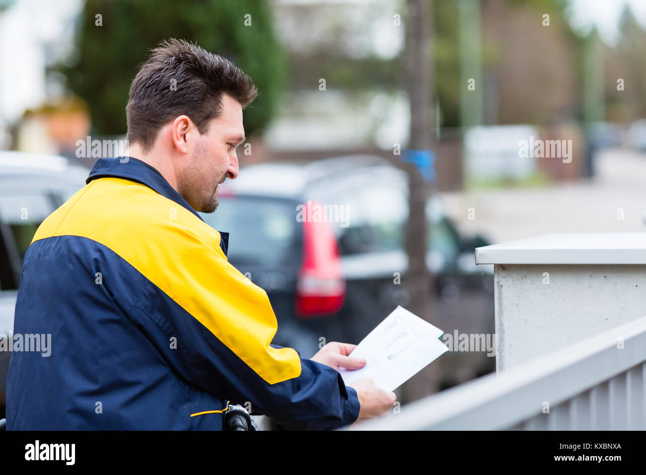 Postman delivering letters to mailbox of recipient Stock Photo - Alamy