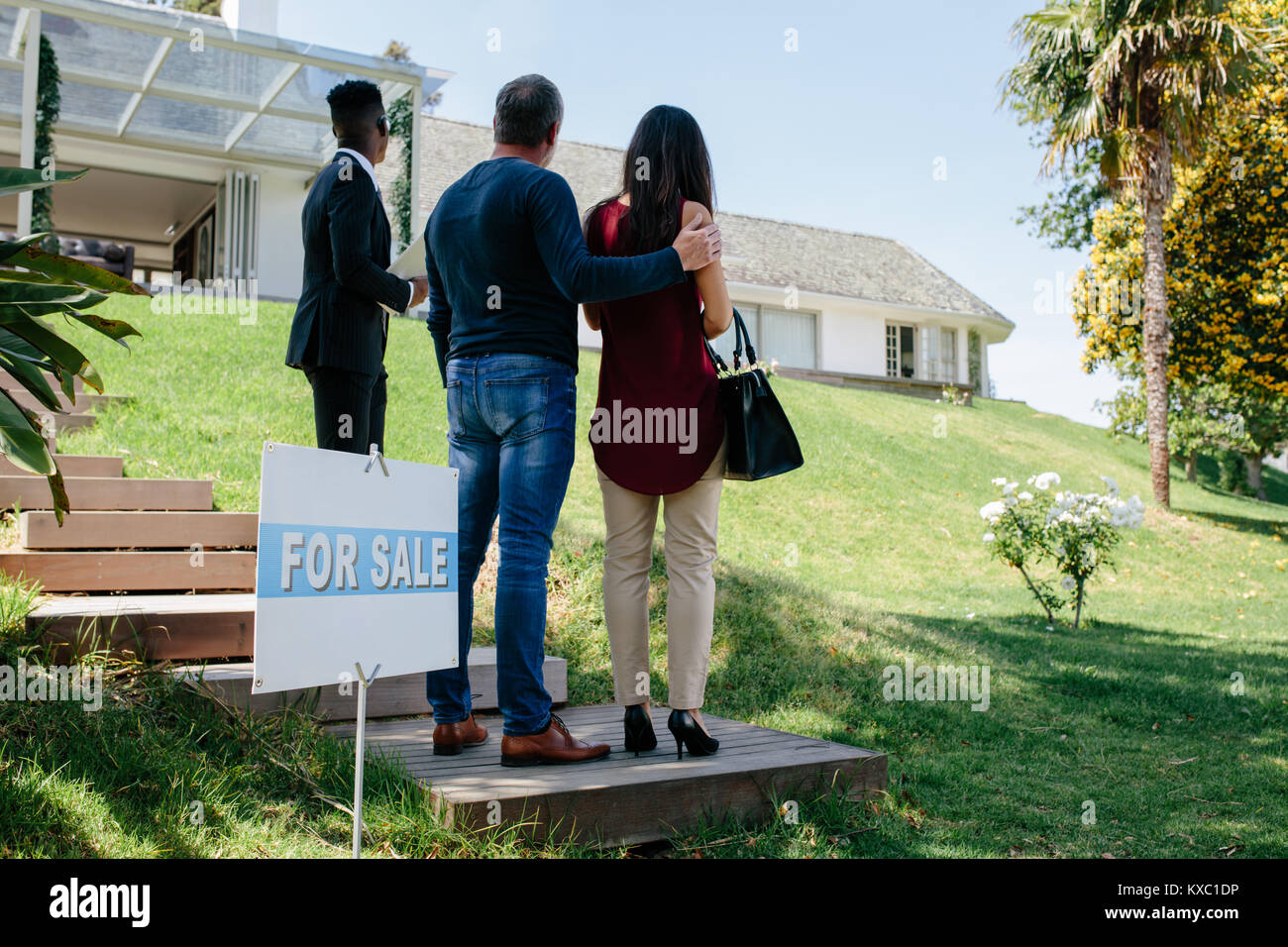 Rear view of couple visiting luxury villa with real estate agent ...