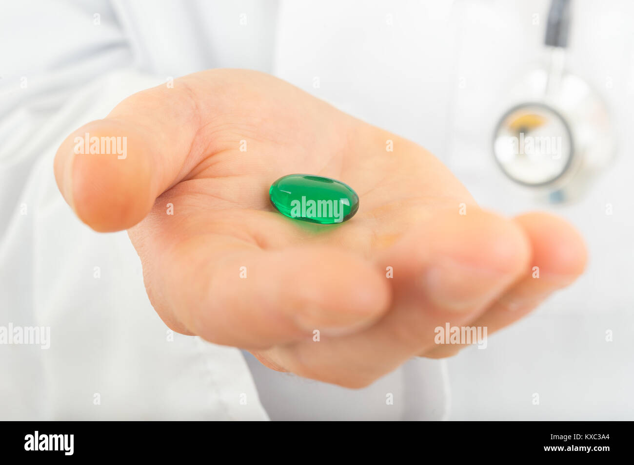 Hand of a doctor holding a green drug pill Stock Photo - Alamy