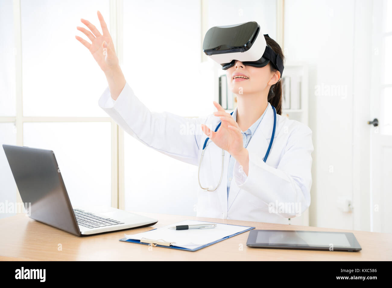 attractive pretty doctor wearing VR technology device looking at online ...