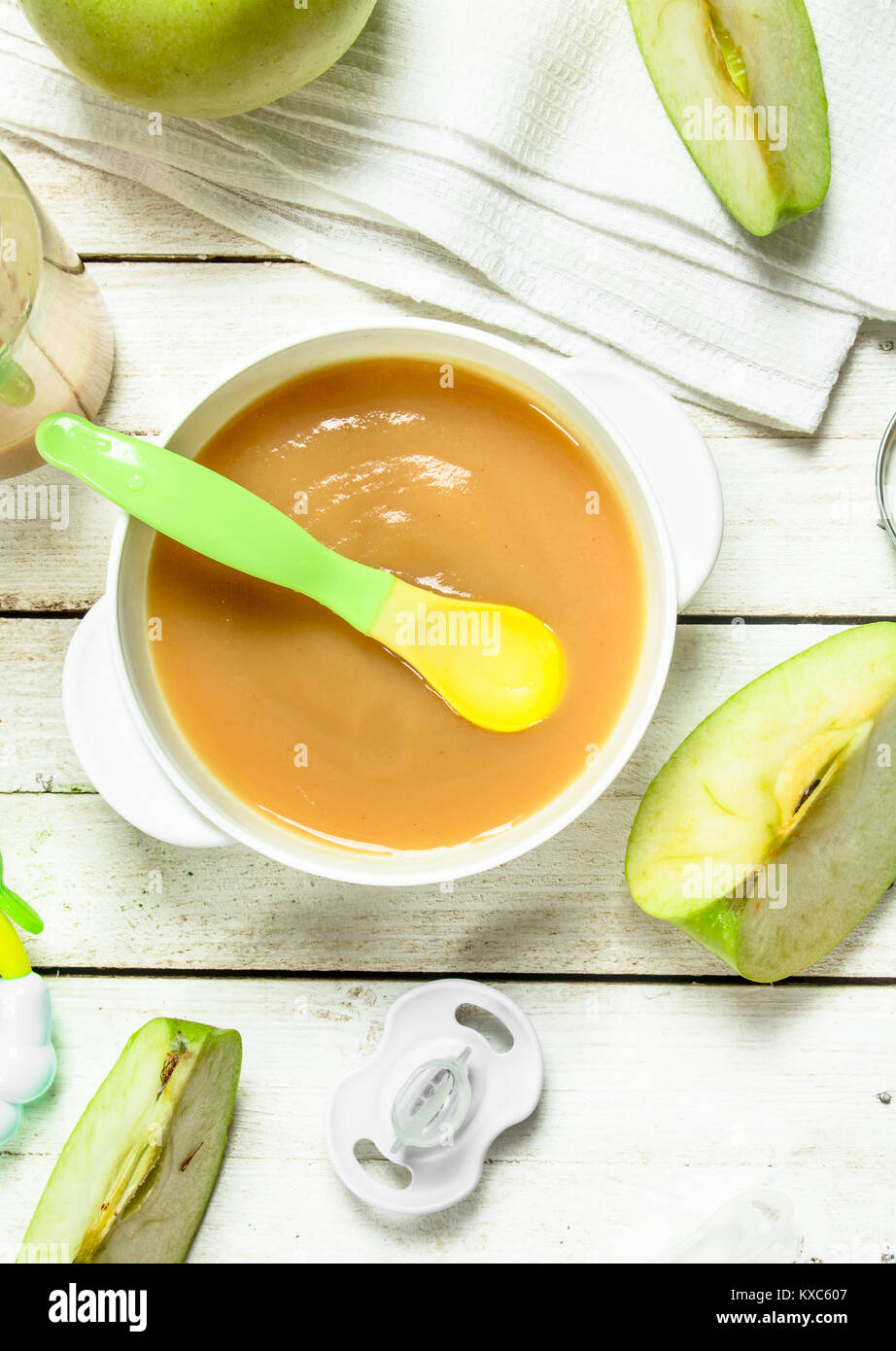 Baby food. Baby puree from fresh green apples. On a white wooden ...