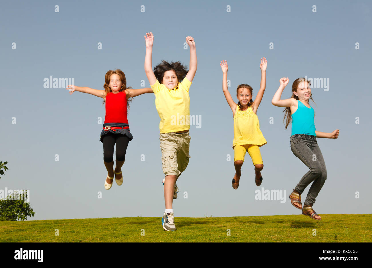 Group of four happy children jumping outside Stock Photo - Alamy