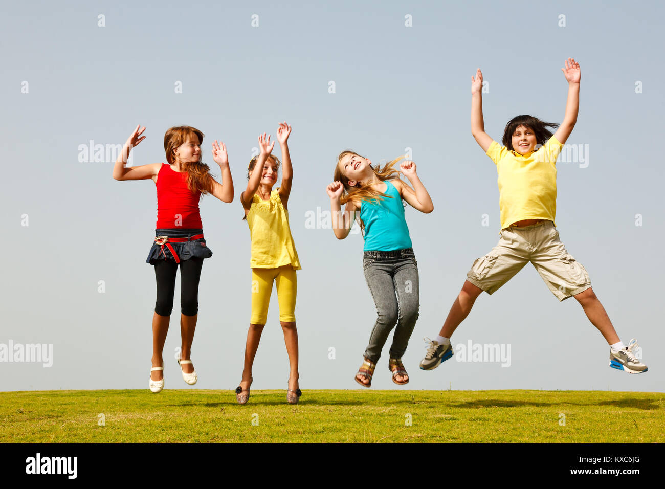 Group of four happy children jumping outside Stock Photo - Alamy