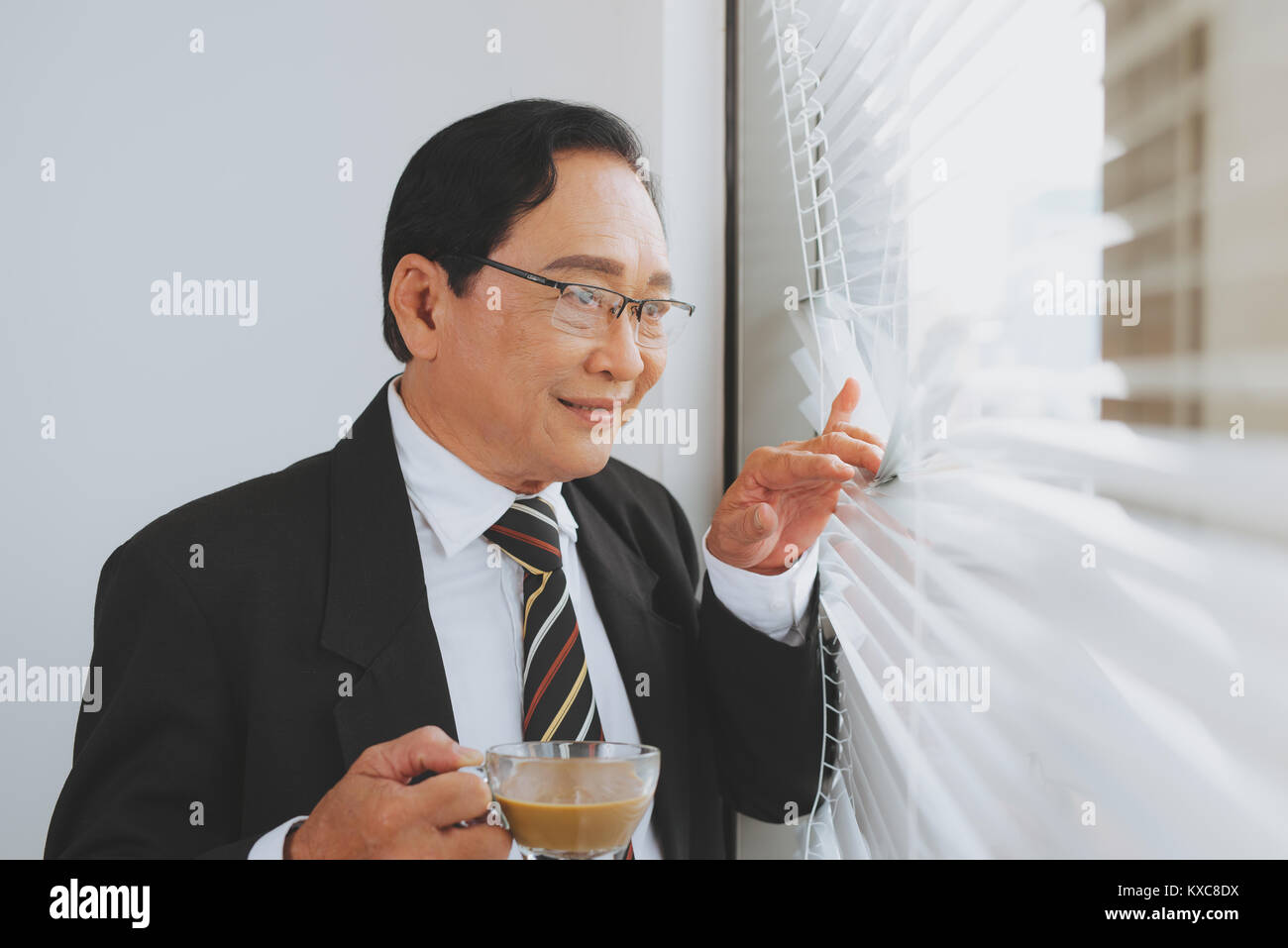 Mature boss contemplating in his office, thinking and looking through ...