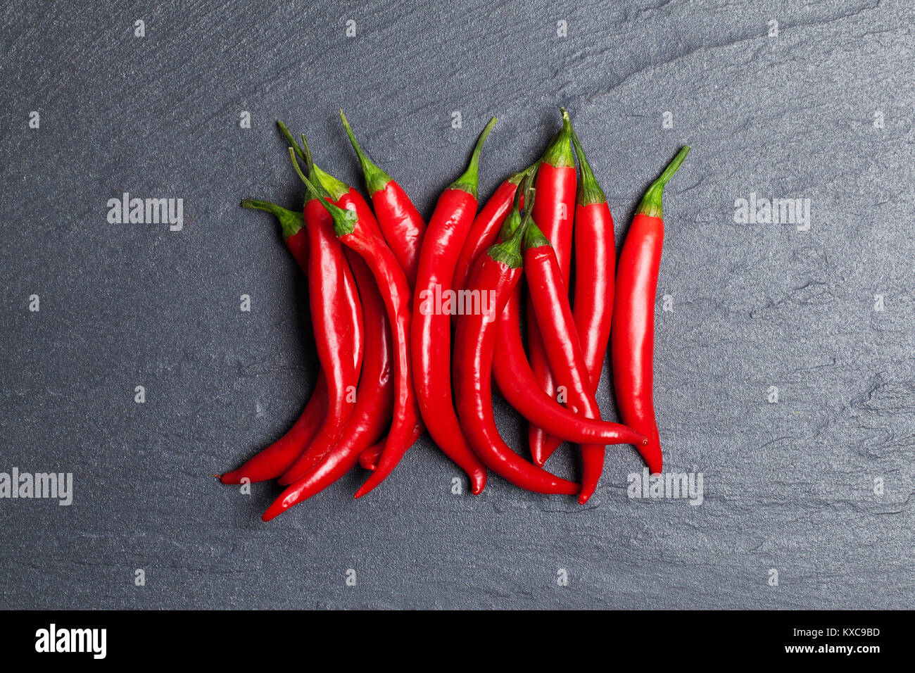 Red fresh chili peppers on a dark slate background Stock Photo - Alamy