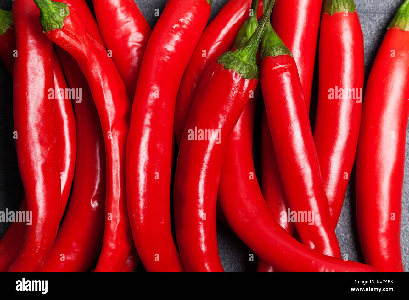 Red fresh chili peppers on a dark slate background Stock Photo - Alamy